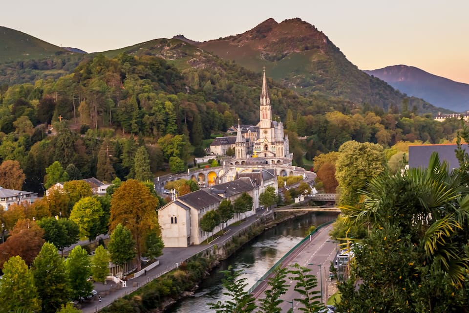 Uma catedral rodeada por vegetação exuberante e um rio.