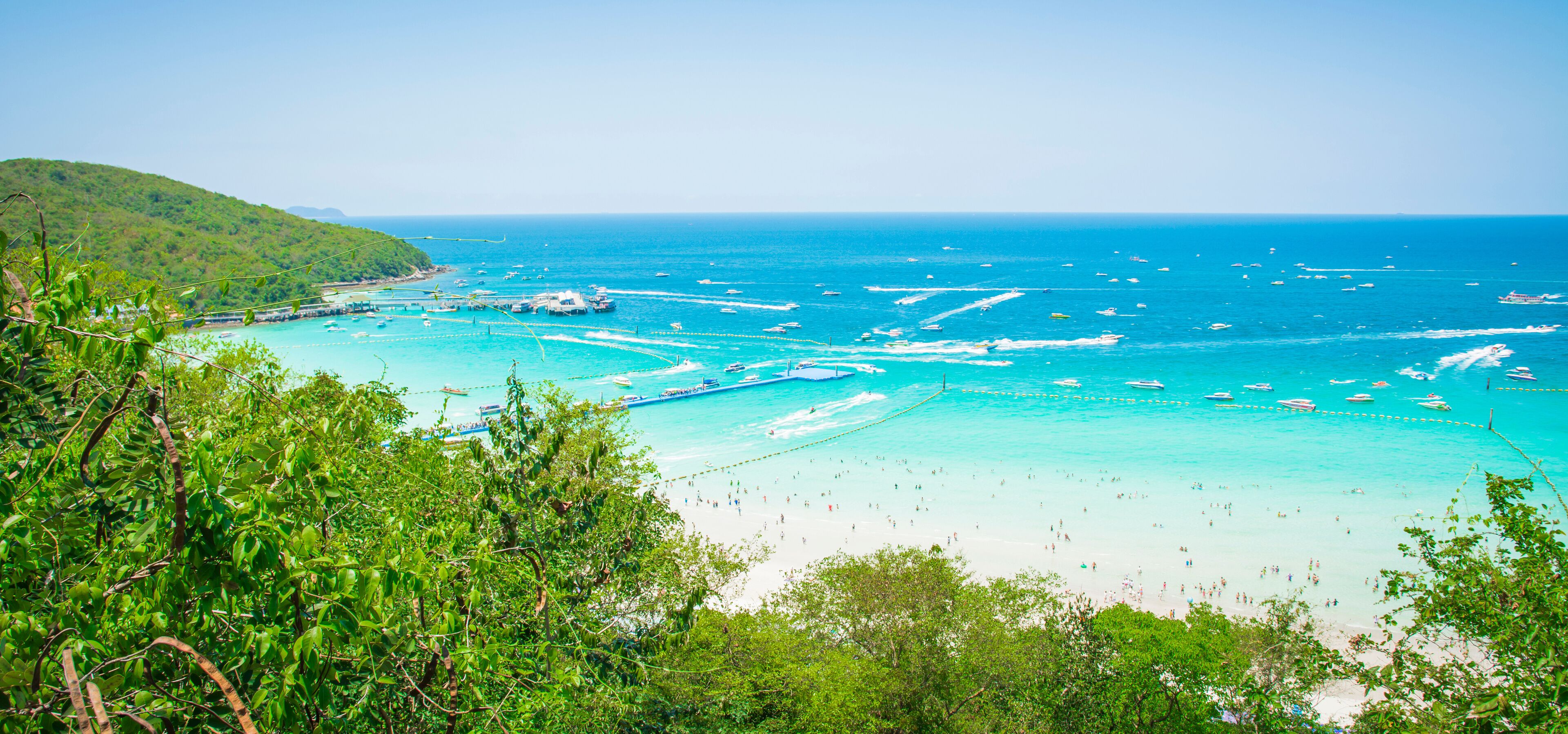 Paisagem costeira com uma praia, águas turquesa cristalinas e barcos.