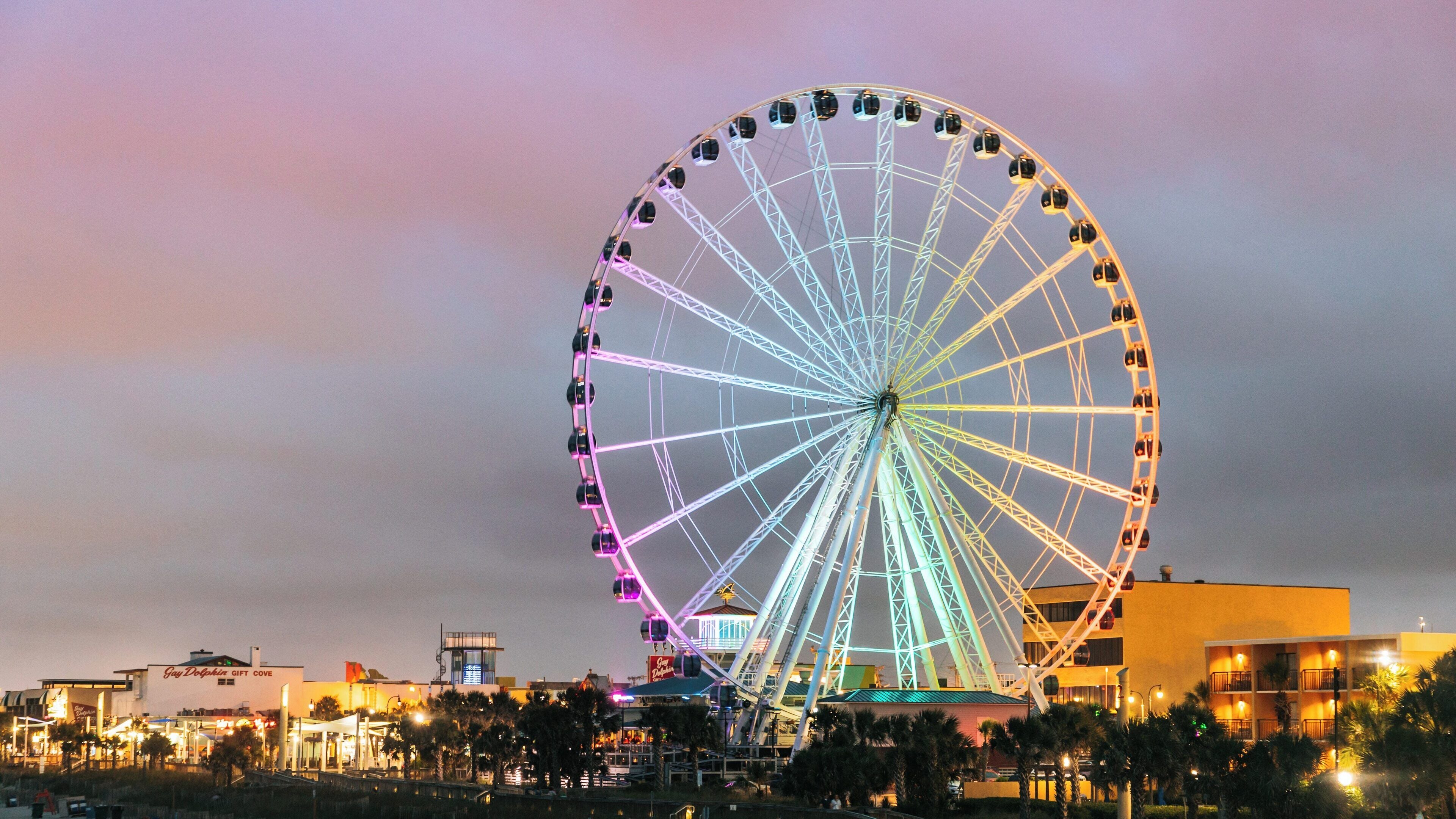 SkyWheel rises above Downtown Myrtle Beach, illuminating the evening sky with bright colors in South Carolina's coastal paradise