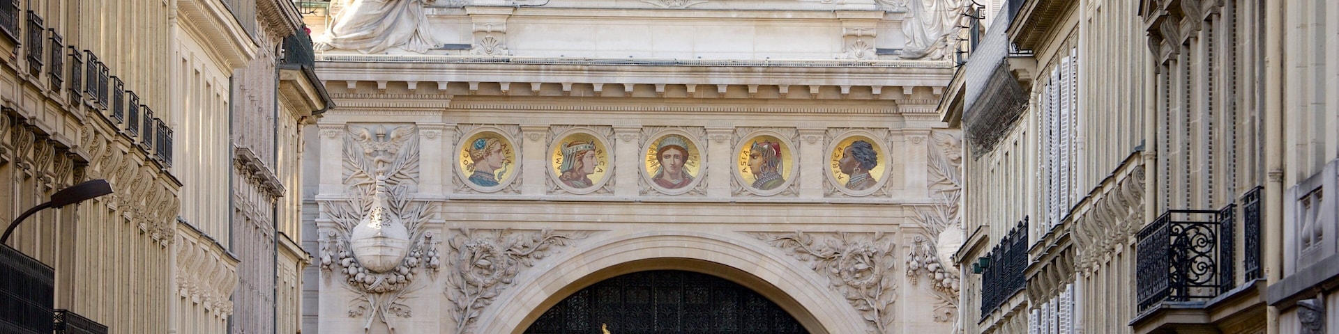 Uma entrada imponente com esculturas ornamentais e a inscrição