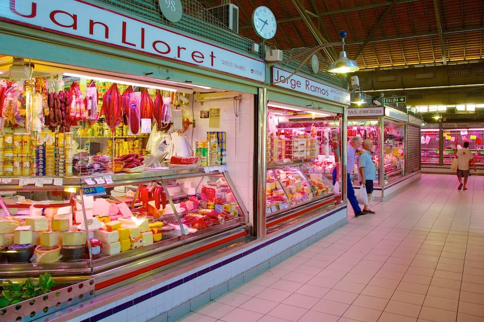 Um mercado com diversos produtos alimentícios à mostra, incluindo queijos e carnes.