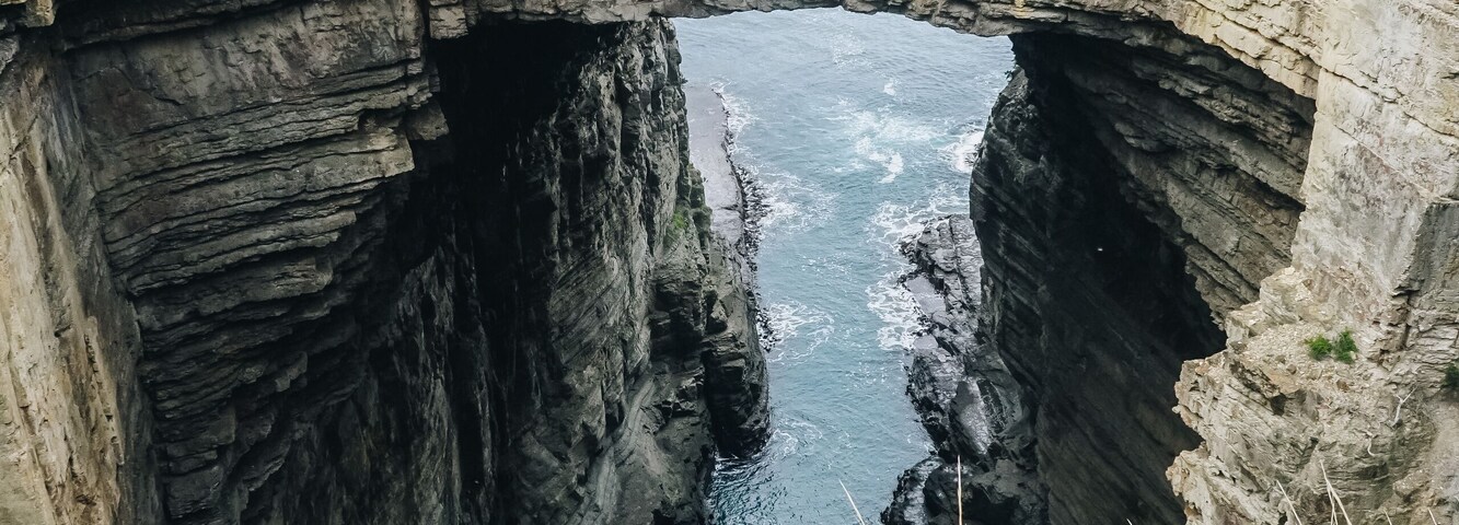 Formação rochosa natural em arco com um rio a correr pelo meio.