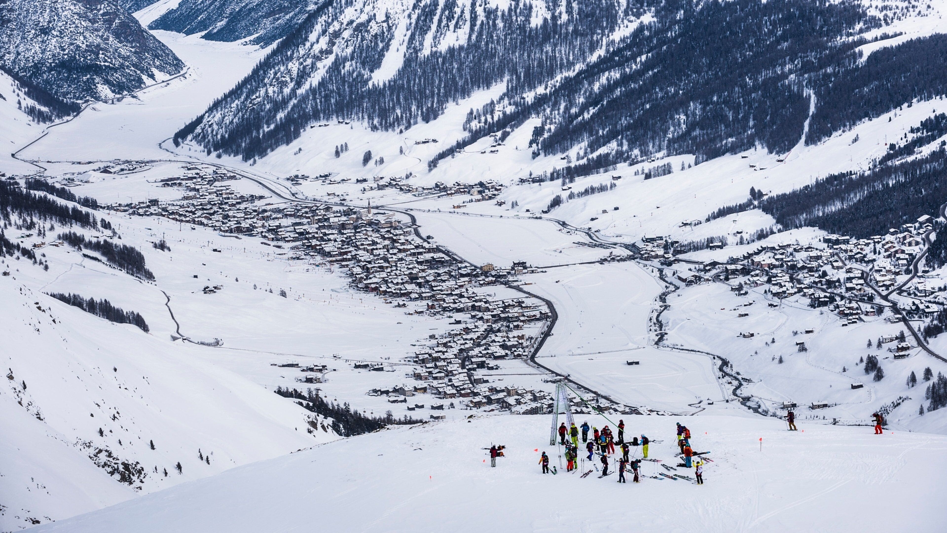 Paisagem montanhosa coberta de neve, com uma cidade situada num vale.