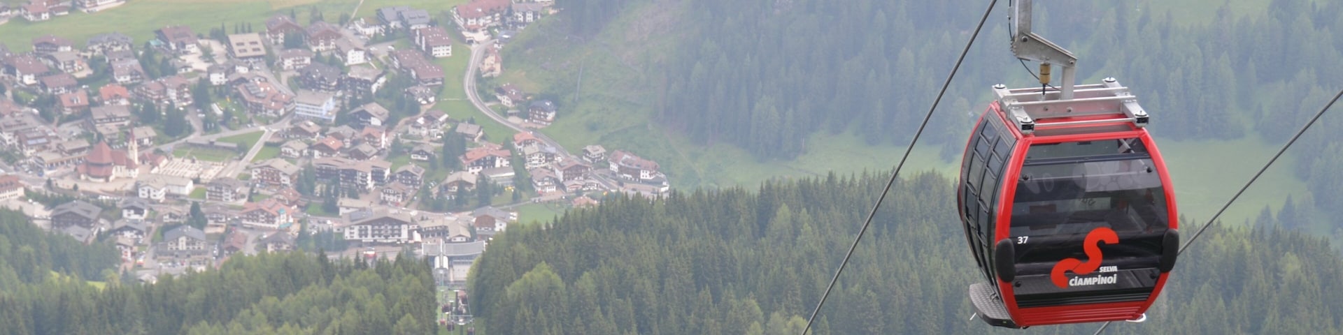 Teleférico sobre uma paisagem montanhosa com uma cidade lá embaixo.