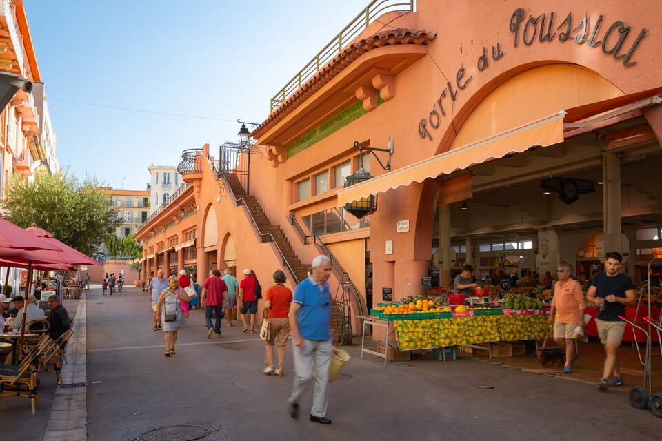 Um mercado de rua movimentado com um edifício laranja proeminente identificado como