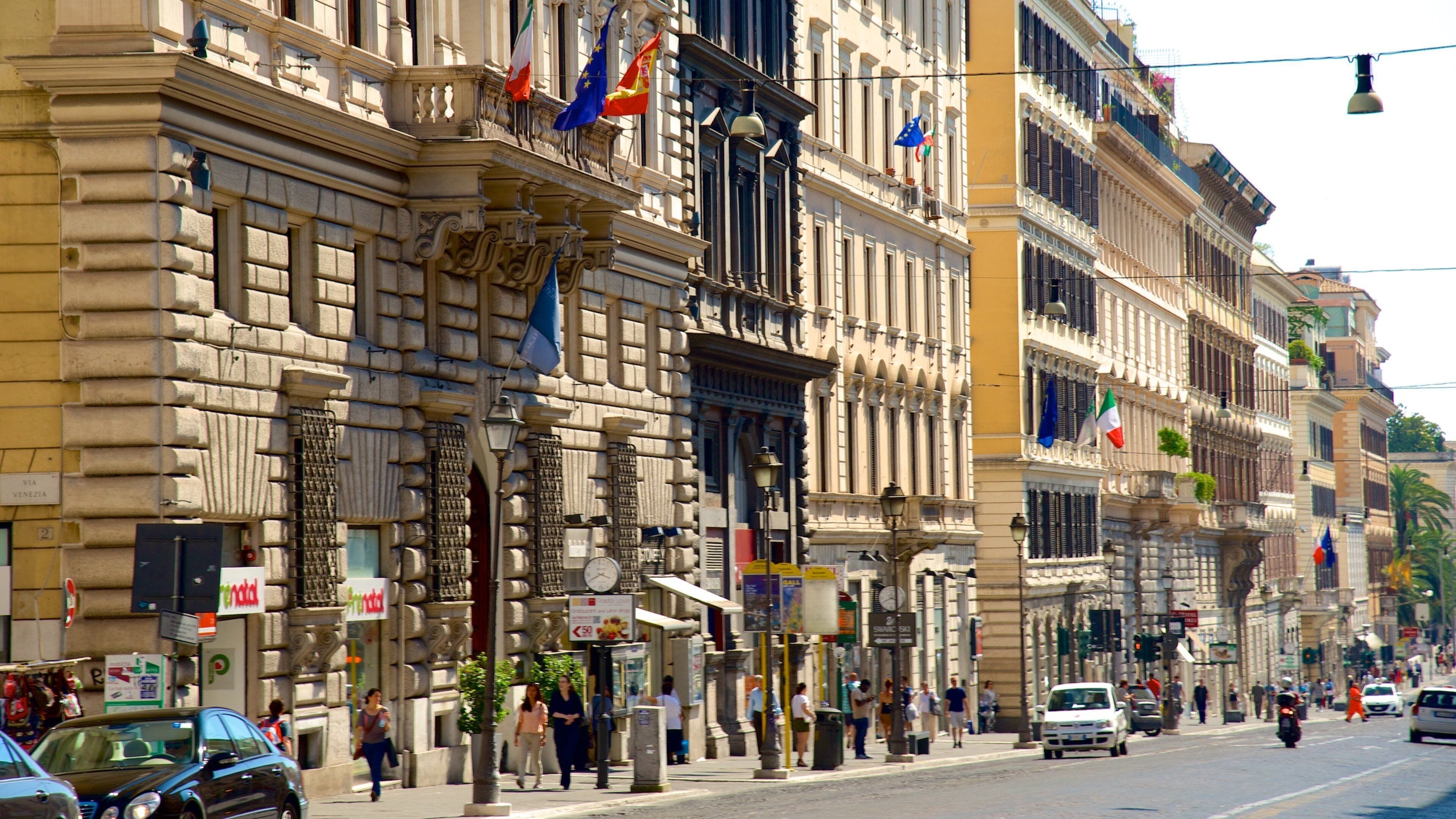 Uma rua flanqueada por edifícios históricos, bandeiras e pedestres.