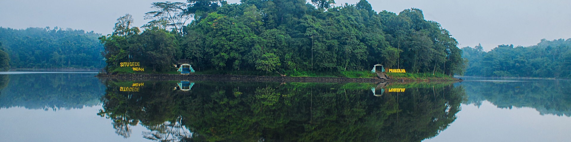 Um lago tranquilo com uma pequena ilha coberta por árvores densas.