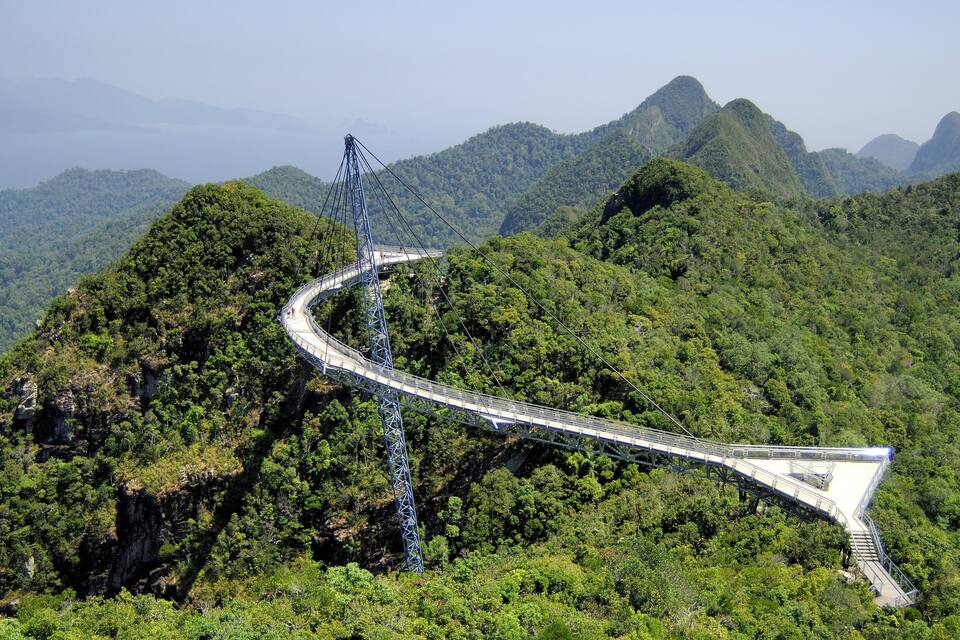 Uma ponte sinuosa sobre uma paisagem montanhosa exuberante.