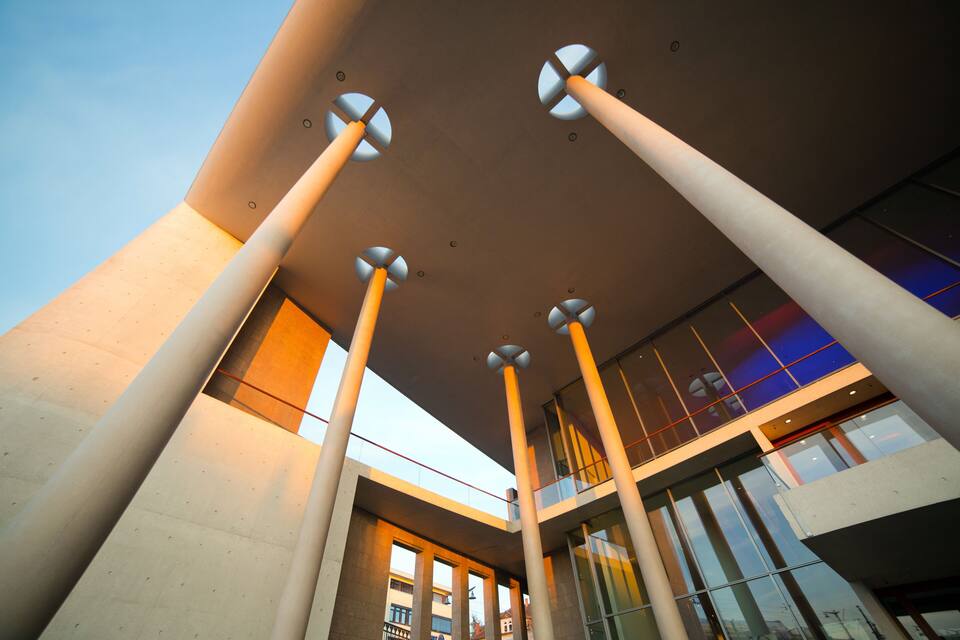 Um edifício moderno com colunas altas e janelas grandes.