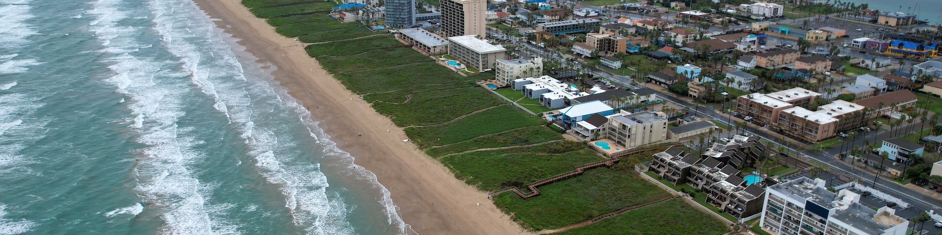 Paisagem costeira com praia, edifícios e uma ponte.