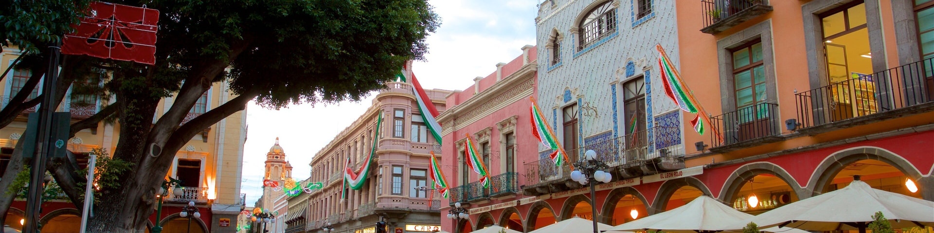 Uma rua repleta de edifícios coloridos, cafés ao ar livre e bandeiras.