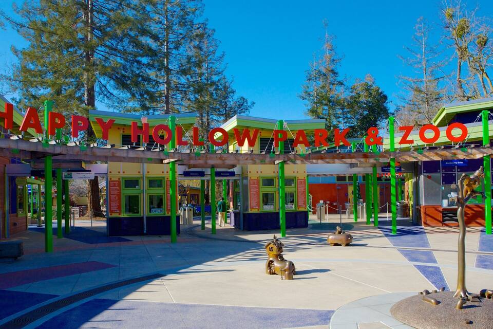 Uma entrada colorida para o zoológico Happy Hollow, com uma placa que diz 'Happy Hollow Zoo'.
