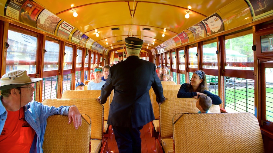 Interior de um autocarro elétrico antigo, com passageiros e um cobrador.
