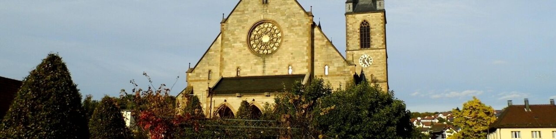 Uma igreja com uma torre do relógio e um banco vermelho em frente.