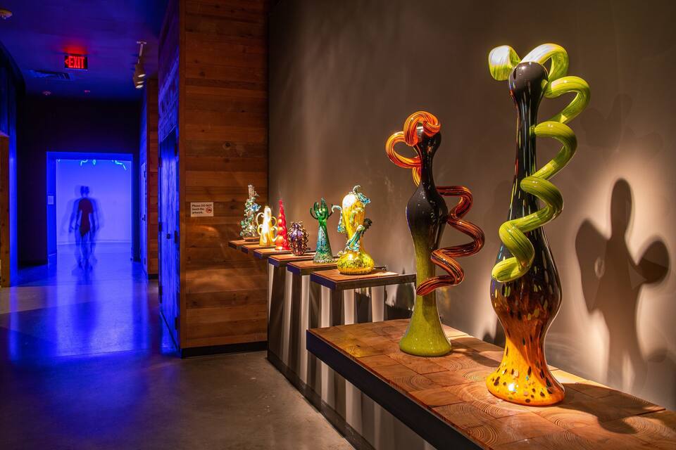 Uma galeria com esculturas de vidro coloridas em exposição.