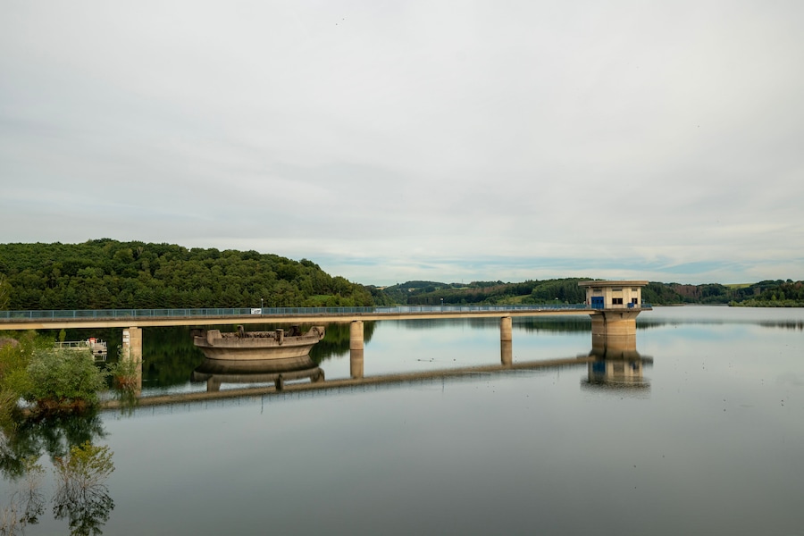 Um lago tranquilo com uma ponte e um pequeno edifício sobre pilares.