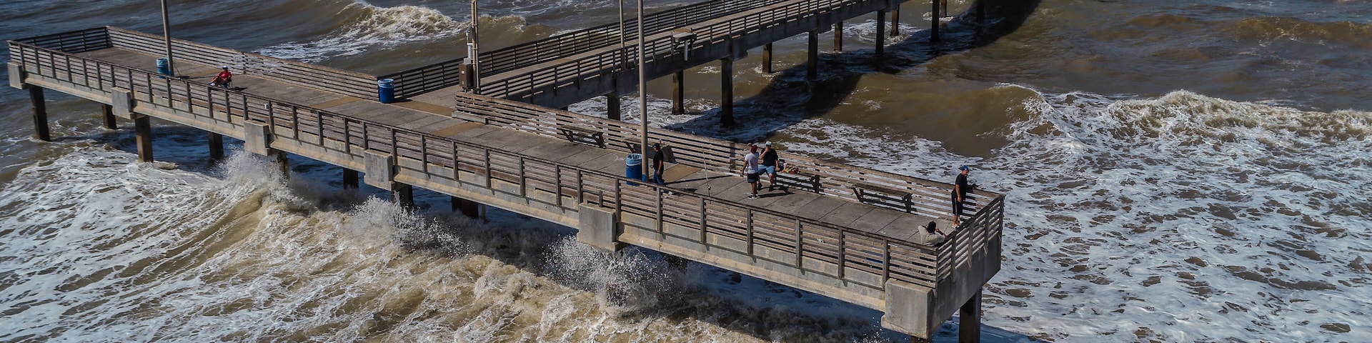 Um cais se estendendo para o oceano, com ondas batendo nele.