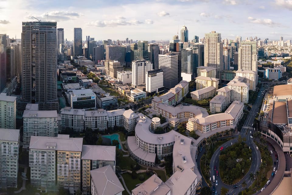Paisagem urbana com edifícios altos, um rotatório e uma combinação de construções residenciais e comerciais.