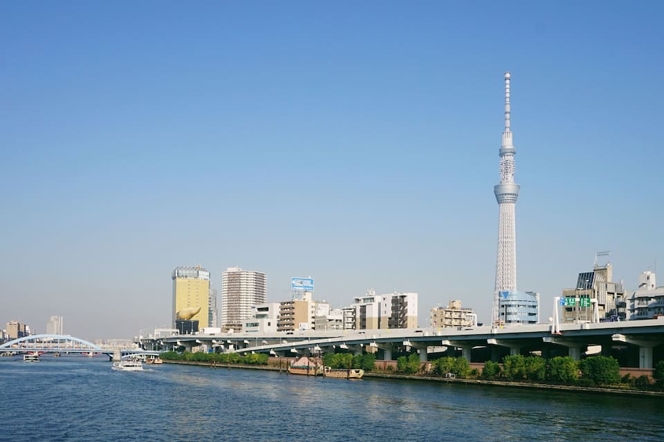 Silhueta urbana com uma torre imponente, uma ponte e um rio.