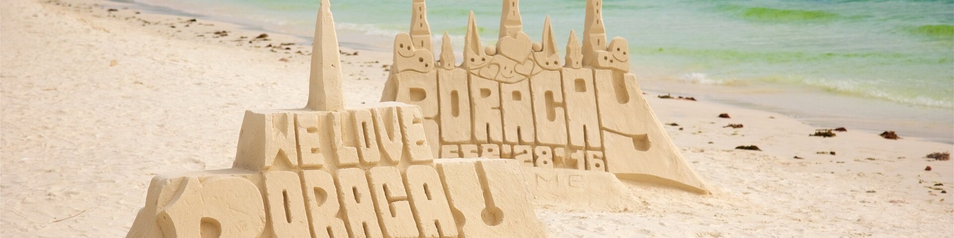 Um castelo de areia na praia, com uma mensagem esculpida.