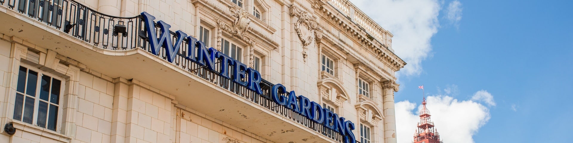 Exterior do Teatro Winter Garden, com detalhes arquitetônicos elaborados e uma torre vermelha ao fundo.