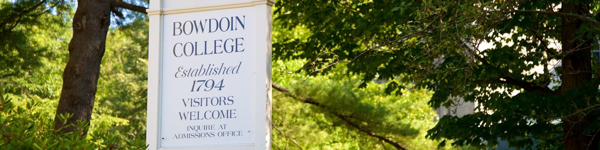 Placa indicativa do Bowdoin College, com uma árvore e vegetação ao fundo.
