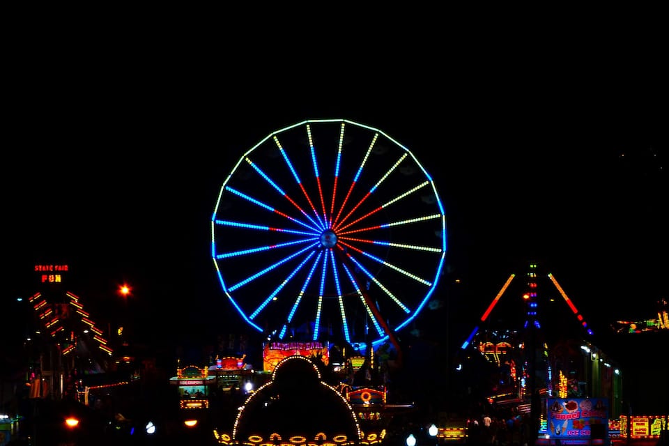 Uma roda gigante bem iluminada à noite, com luzes coloridas.