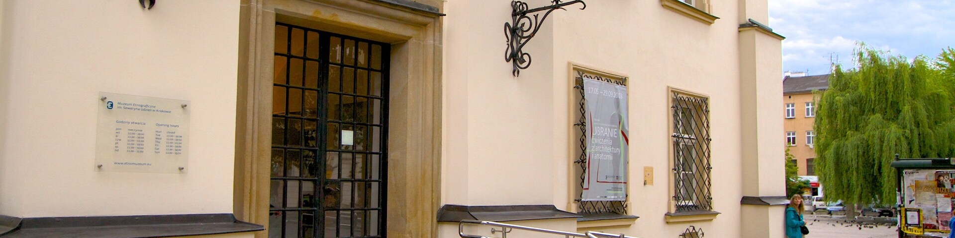 A entrada do Muzeum Etnograficzne, com um portão de metal, uma placa indicativa e um poste de luz.