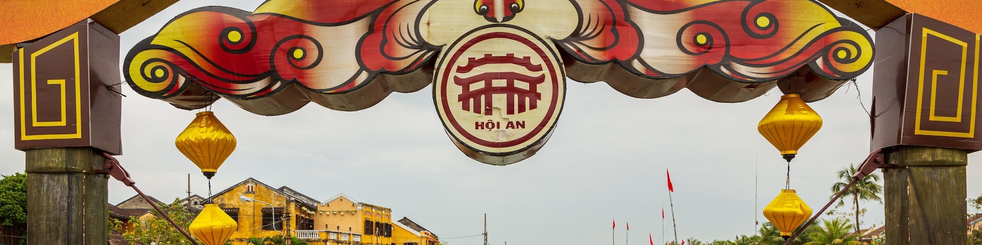 Um portão tradicional com design de dragão e a palavra "Hội An" no centro.