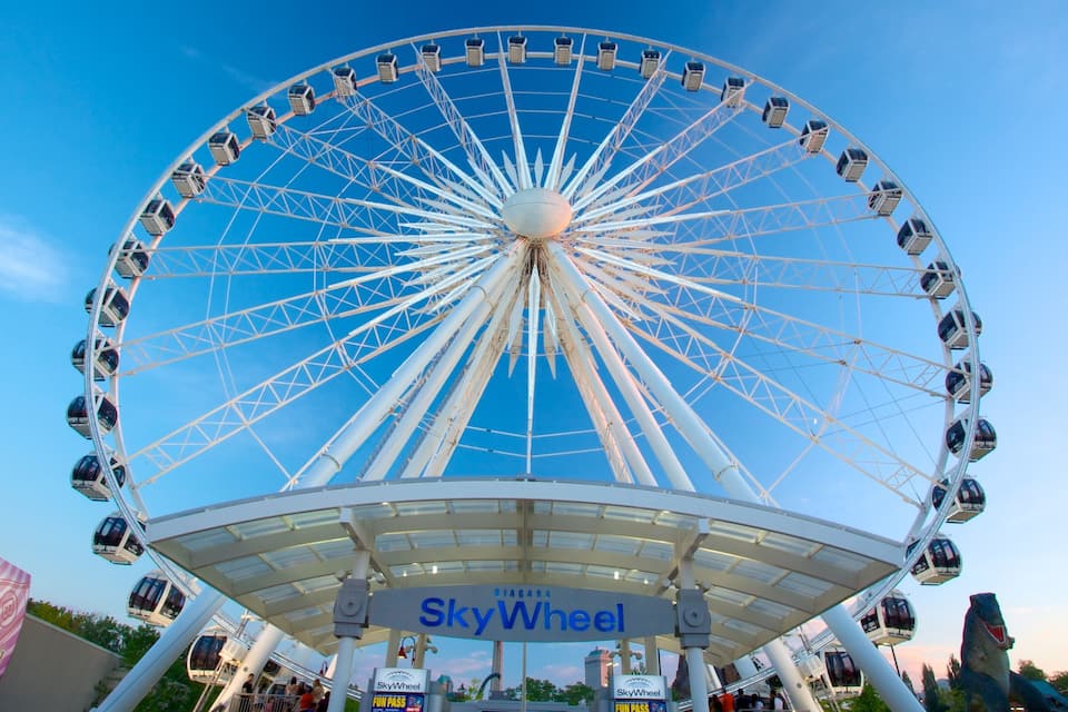Uma grande roda-gigante com cabines rotuladas como "SkyWheel" em um parque temático.