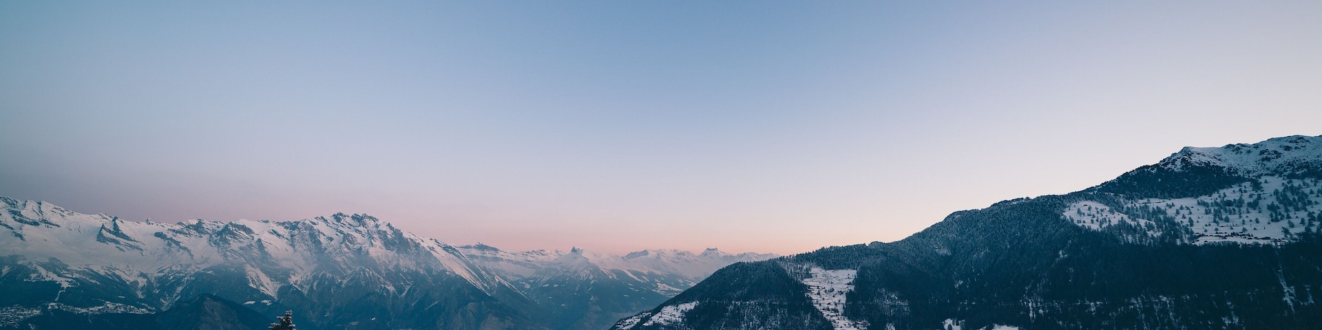 Uma cadeia montanhosa coberta de neve com uma cidade aninhada no vale.