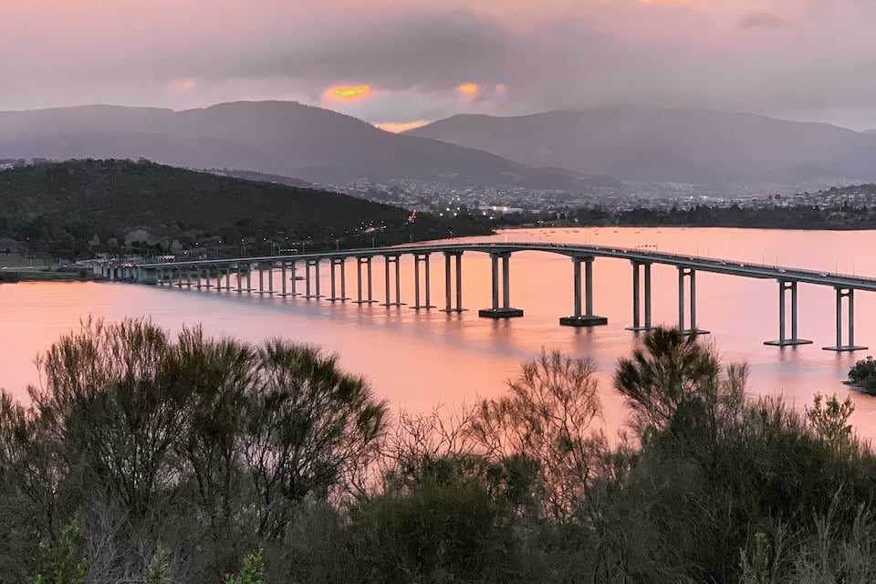 Uma ponte sobre a água, com montanhas ao fundo.