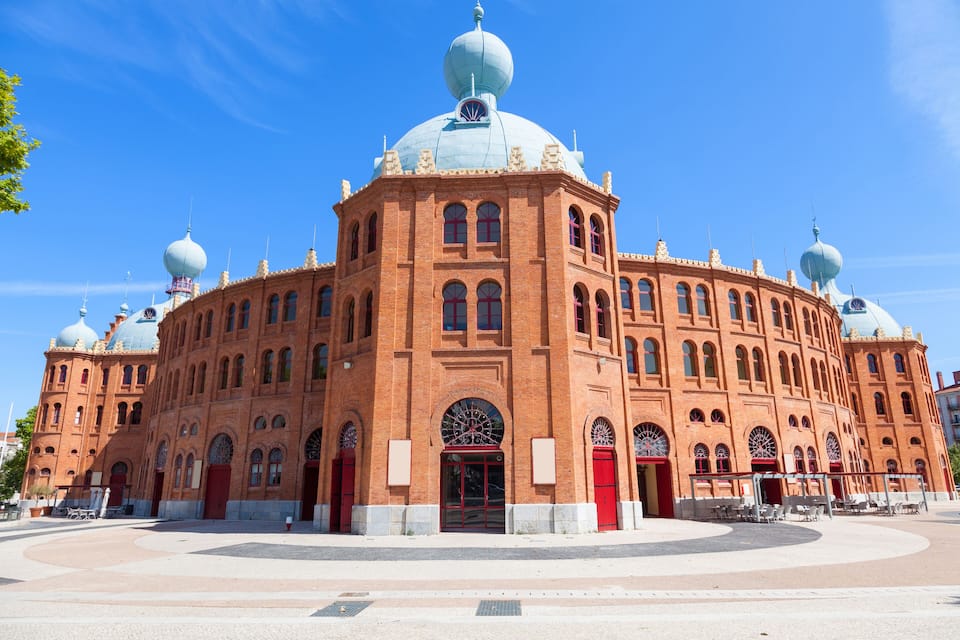 Um grande edifício de tijolos vermelhos com várias cúpulas e janelas em arco.