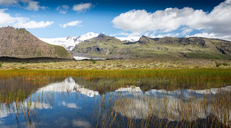 Paisagem montanhosa com um lago reflexivo e picos nevados.