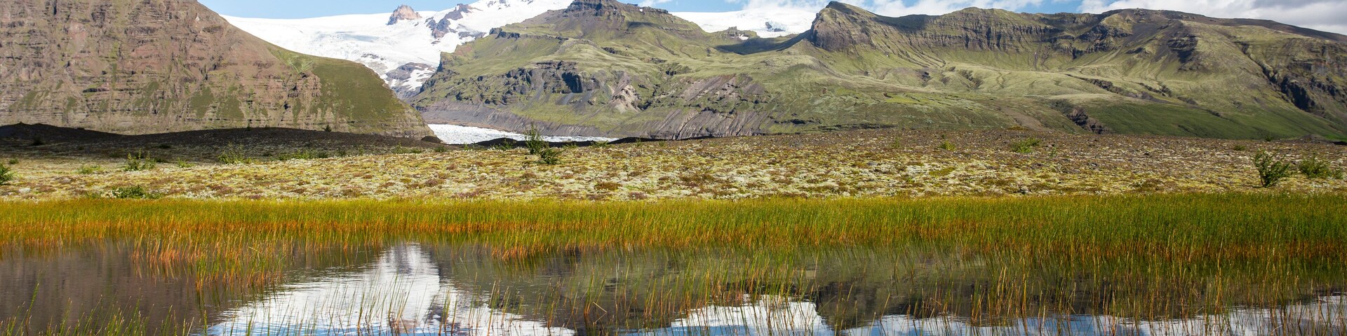 Paisagem montanhosa com um lago reflexivo e picos nevados.