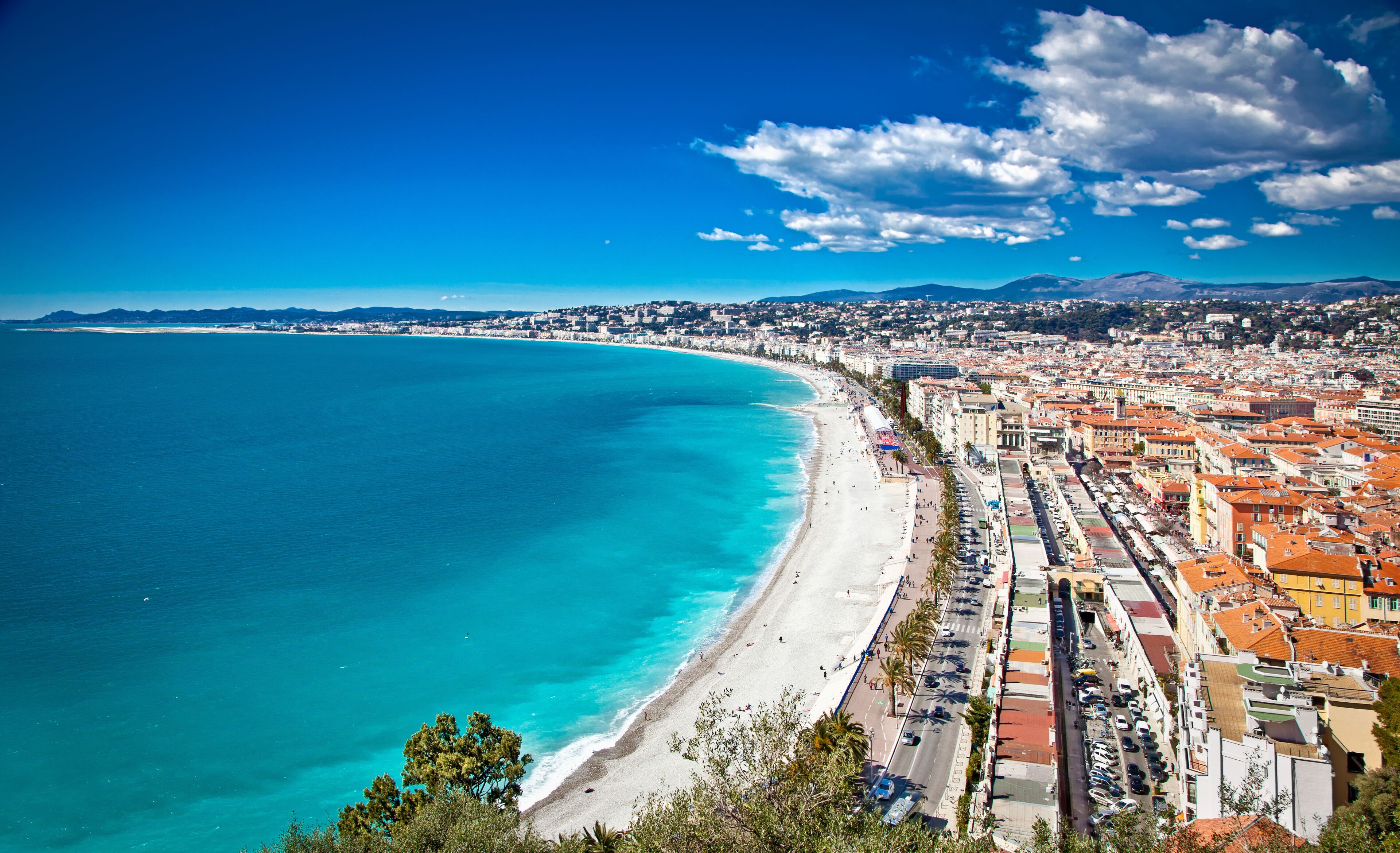 Uma cidade costeira com uma praia extensa, águas azuis cristalinas e uma área urbana densamente construída com edifícios coloridos.