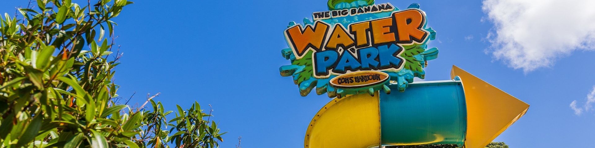 Um letreiro colorido para o Parque Aquático Big Banana, com um grande escorregador aquático amarelo e azul.