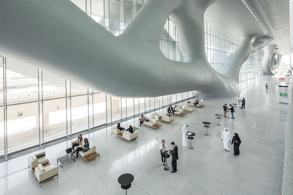 Interior moderno de aeroporto, com amplas janelas de vidro, áreas de assento em branco e um design de teto único.
