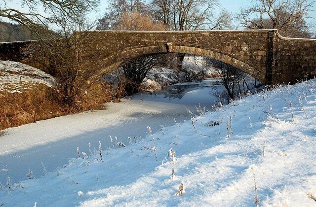 Uma ponte de pedra sobre um rio coberto de neve.