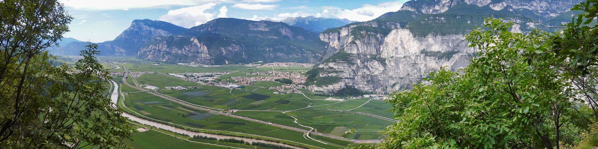 Um vale com campos em socalcos, um rio sinuoso e uma cordilheira ao fundo.