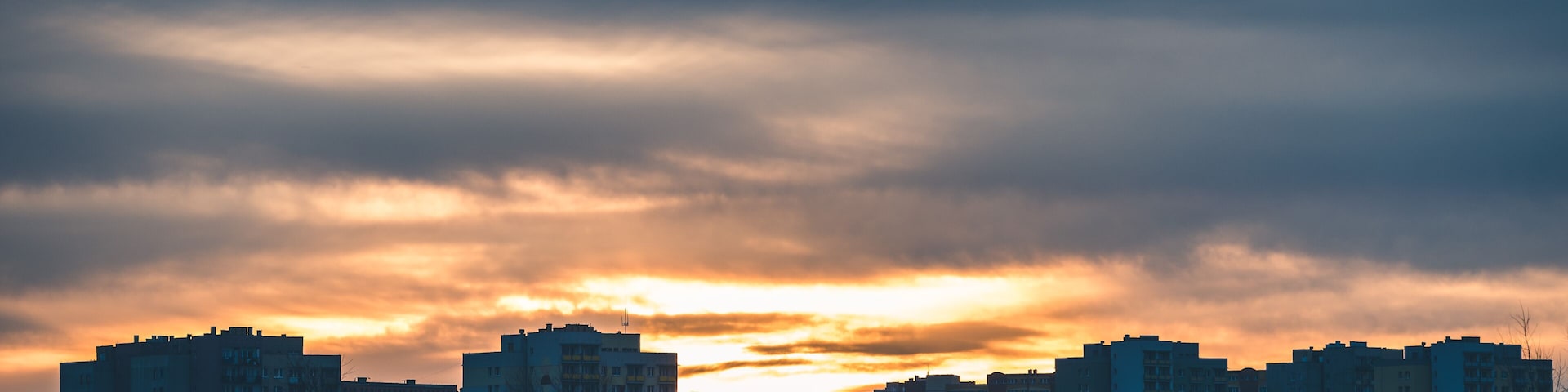 Silhuetas de edifícios contra um céu colorido ao pôr do sol.