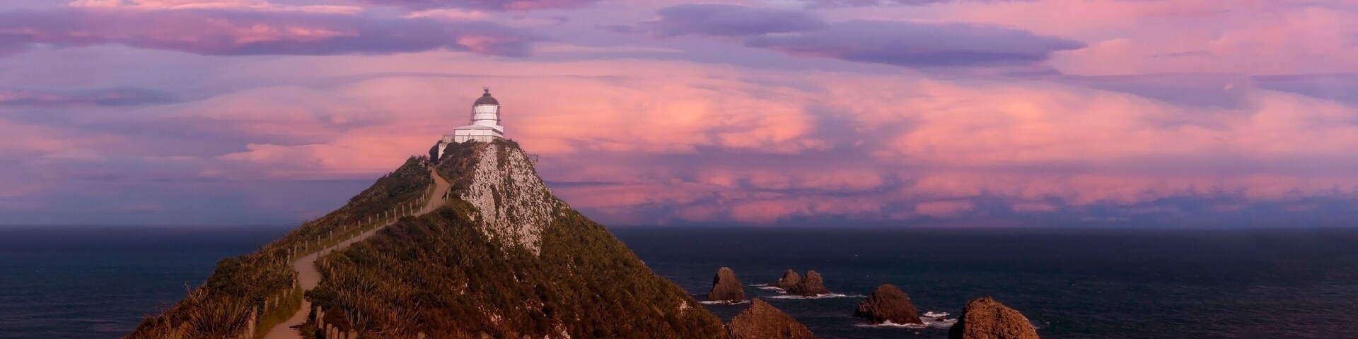 Uma estrutura em forma de cúpula branca numa colina rochosa, com vista para o litoral.