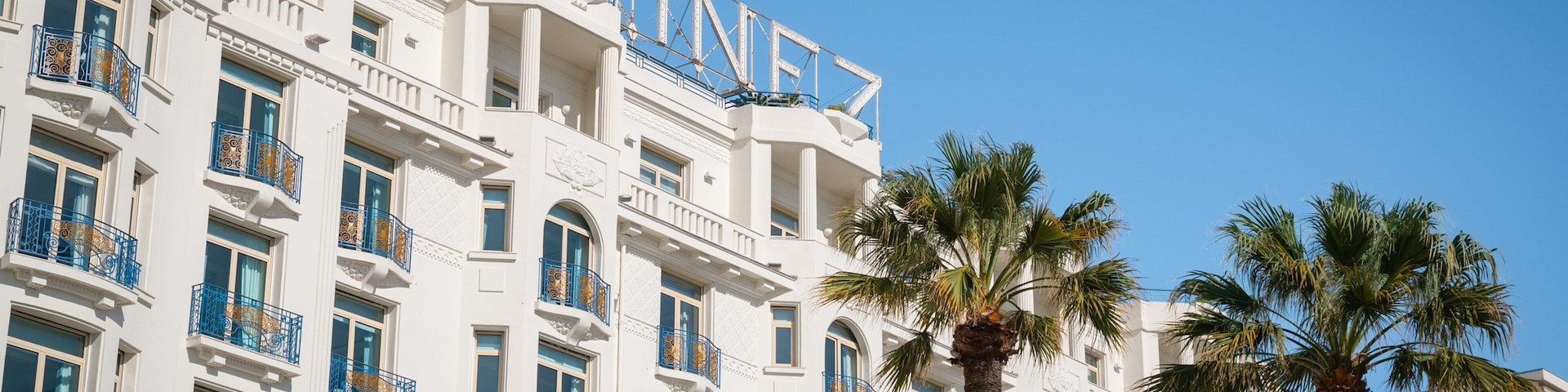 Um edifício branco com varandas azuis e o nome "MARTINEZ" na fachada.