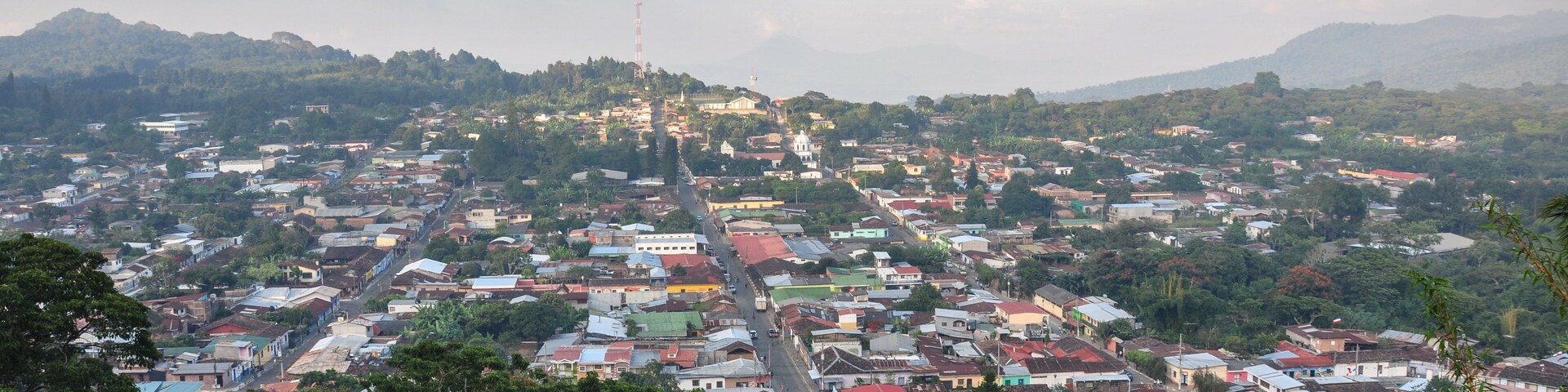 Uma cidade aninhada num vale, com uma igreja imponente e uma torre no topo da colina.