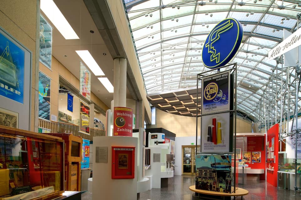 Um espaço de exposição interior com teto de vidro, exibindo diversos artefatos e exposições históricas.