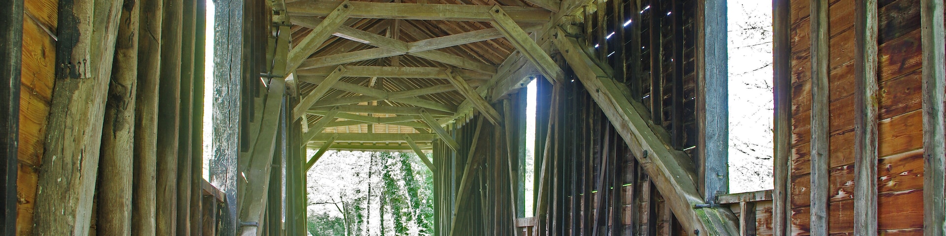 Le Pont-Chrétien-Chabenet (Indre). Le pont couvert. Le pont de bois, couvert, enjambe la Bouzanne. Ce pont doit être, en France, le seul ouvrage en bois entièrement couvert (le pont couvert moderne de Saint-Gervais-sous-Meymont reste une exception, il n'est pas fermé sur les côtés). Classé monument historique le 20 juillet 1992, son édification a été autorisée par la préfecture de l’Indre en 1855 suite à une demande du Comte de Poix, seigneur de Chabenet. Le pont a été restauré en 2001. Selon la version locale, le pont couvert aurait été bâti, entre 1847 et 1854, lors de la construction du tronçon Châteauroux/Argenton-sur-Creuse du chemin de fer du Centre (ligne Paris-Toulouse), pour permettre aux ouvriers italiens travaillant au percemement du tunnel et au chemin du viaduc des Roches, de franchir quotidiennement la Bouzanne. La traversée de la Bouzanne, effectuée jusque là en barque, avait coûté le vie à neuf d'entre eux le 20 avril 1847, leur embarcation ayant été emportée par une crue. En outre la couverture du pont offrait un abri pour le repas des ouvriers. Selon une autre version, le pont aurait été construit vers 1860 par le comte de Poix pour desservir ses domaines. Le tronçon Châteauroux-Limoges de la ligne Paris-Toulouse sera confié au jeune ingénieur Jules Carvallo*, né en 1820 au sein d'une famille d'origine juive portugaise. Peu de temps après sa sortie des Écoles polytechnique et des ponts et chaussées, Il doit donc superviser la réalisation du tunnel des Roches et le viaduc enjambant la Bouzanne*. Il va être confronté à la dure réalité du terrain. "Les chantiers de chemins de fer avaient la réputation d'être ingérables. Ils réunissaient un nombre impressionnant d'ouvriers, de corps de métiers et de provenances géographiques. Les conditions de vie et de travail y étaient en outre épouvantables. C'est pourquoi les bagarres étaient quotidiennes et d'une grande violence." (Léandre Boizeau*) Jules Carvallo, qui n'a pas encore 30 ans, sera donc confronté à la noyade des neuf ouvriers qui traversaient la Bouzanne en crue, il devra également s'interposer, armé, à des ouvriers grévistes, il sera même accusé d'actes crapuleux. Après ce séjour mouvementé au Pont-Chrétien de1845 à 1852, l'homme est devenu "influent, respectable et respecté." Les difficultés de Carvallo s'inscrivent dans une période, par ailleurs plutôt tragique dans la région, avec les émeutes de Buzançais. Dans les campagnes de l’Indre, durant l'hiver de 1846/1847, la maladie de la pomme de terre, la spéculation sur le blé et le chômage saisonnier aggravent les conditions de vie très précaires du petit peuple des villages, journaliers agricoles et artisans. On se révolte contre les profiteurs, les usuriers, les propriétaires. La “Jacquerie de Buzançais*” restera l'affaire la plus considérable, mais ce ne sera pas la seule, 35 localités de l'Indre veront des émeutes. La radicalité des actions et la dureté de la répression, provoquent la réaction de personnalités, comme George Sand*, Gustave Flaubert, Victor Hugo, ou encore Karl Marx*. Le trajet aurait pu, sans doute, être plus simple et moins coûteux, mais on peut penser que le Comte De Poix, important actionnaire des chemins de fer d’Orléans, a fait revoir le tracé pour qu’il évite ses vignes et son château. Son wagon spécialement aménagé était stationné en gare de Chabenet. Léandre Boizeau, instituteur dans l'Indre, l'un des membres fondateurs du magazine saisonnier (plus quelques numéros spéciaux) berrichon, la Bouinotte. Jules Carvallo (1820-1915), publiera une "étude sur la Stabilité des voûtes" en 1853. En 1860, il sera l'un des six signataires de l'appel fondateur de "l'Alliance Israélite universelle". Cette fondation est une conséquence de l'affaire de Damas (suite de la disparition d’un moine franciscain à Damas, des Juifs de la ville, accusés de crime rituel, sont arrêtés et torturés ; certains meurent), et de l'affaire Mortara. (Edgardo Mortara, né en 1851 dans une famille juive de Bologne, est enlevé par les autorités papales car il avait été baptisé à l’âge d’un an par la servante catholique de la famille. Il n’est jamais rendu à sa famille et devient même prêtre). Au cours d'une émeute à Buzançais, initiée par le vol d'un convoi de blé - 1060 décalitres - motivé par la famine, entre le 13 et le 15 janvier 1847, des émeutiers tentent d'assassiner le meunier Cloquemin et les propriétaires Brillant et Gaulin après avoir pillé leurs maisons. Enfin, battent à coups de bâton, de fourche et de sabots M.Huard-Chambert, propriétaire bourgeois qui avait tiré pour se défendre sur Venin, chef des émeutiers, l'abattant net. 26 accusés seront jugés par la Cour d'assise de l'Indre (le jury a été recruté chez les propriétaires, on écartera le seul juré qui serait "hostile" au gouvernement) pour "pillage, assassinat, tentatives d'assassinat et d'incendie". Les avocats des émeutiers, maîtres Protade-Martinet et Rollinat, (le père de l’écrivain Maurice Rollinat) mettent en avant la misère du peuple dans son ensemble : « Le peuple ne sait, ne voit qu’une seule chose, c’est qu’on emporte au loin le blé, sa seule nourriture », « Les accusés n’ont été que des instruments qui ont exécuté une sentence prononcée par la multitude ». Le 4 mars 1847, Baptiste Bienvenu, Louis Michot et François Velluet, seront condamnés à mort par le tribunal de Châteauroux, quatre aux travaux forcés à perpétuité, les dix-huit autres à des peines plus ou moins fortes, et à l'exposition publique sur la place de Buzançais, un seul sera acquitté (Bezard). Baptiste Bienvenu, Louis Michot et François Velluet seront guillotinés en place publique, à Buzançais, le 16 avril 1847. Les trois guillotinés du 16 avril, sont : - Louis Michot, 20 ans, ouvrier sabotier, célibataire, hab. Châteauroux, rue des Ponts. - François Velluet, 37 ans, garde particulier, marié 4 enf., hab Bonneau commune de Sainte-Gemme. - Baptiste Bienvenu, 25 ans, journalier, célibataire, hab. Buzançais. George Sand écrit à son cousin en février 1847 "C’est affreux, et entre ceux qui vont comparaître aux assises et ceux qui vont les accuser, je ne sais trop lesquels ont mérité les galères". "La maladie de la pomme de terre et les mauvaises récoltes de 1845 et de 1846 accentuèrent l'effervescence générale dans le peuple. Le renchérissement de la vie en 1847 provoqua en France comme sur tout le reste du continent des conflits sanglants. Face aux orgies scandaleuses de l'aristocratie financière, c'était la lutte du peuple pour les moyens d'existence les plus élémentaires ! A Buzançais, on exécuta les émeutiers de la faim à Paris des escrocs repus étaient soustraits aux tribunaux par la famille royale !". (K. Marx - Les luttes de classes en France)