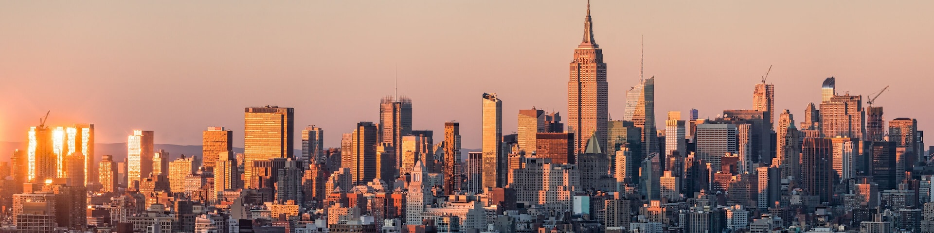 Paisagem urbana com muitos arranha-céus, incluindo um edifício alto notável com um pináculo.