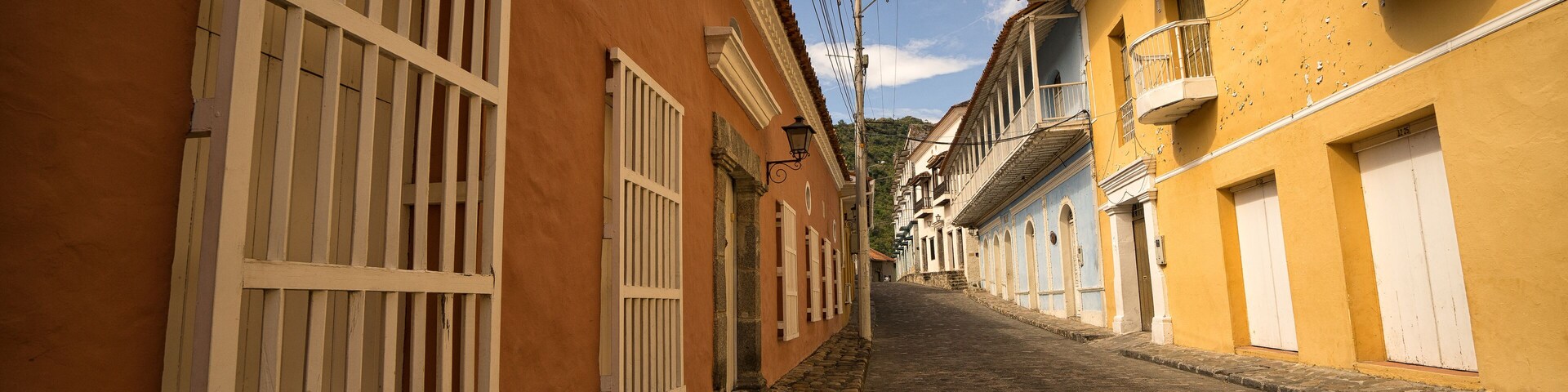 Ruas de paralelepípedos ladeadas por edifícios com venezianas brancas e varandas.