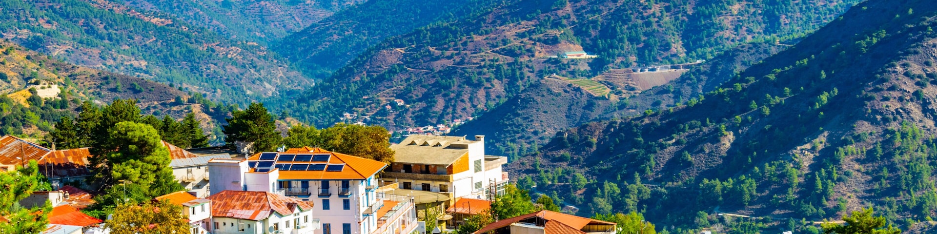 Uma vila montanhosa com campos em socalcos, edifícios tradicionais com telhados vermelhos e vegetação exuberante.