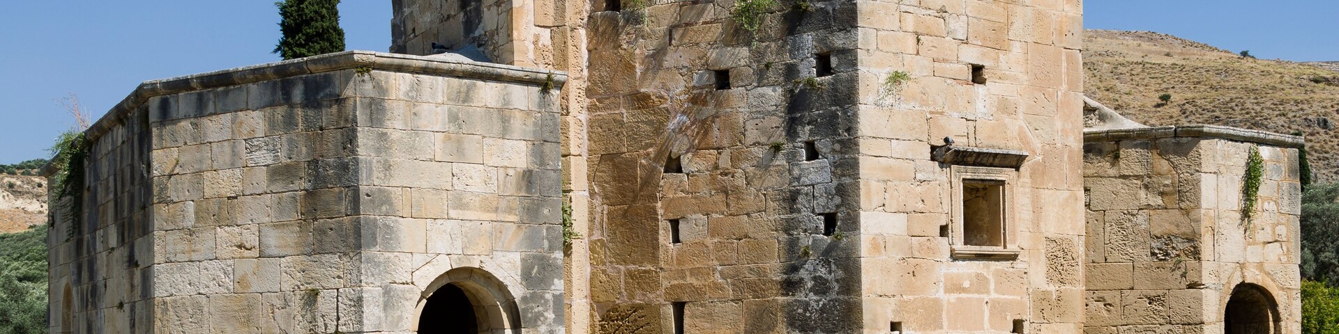 Uma estrutura antiga de pedra com portas em arco e telhado plano.